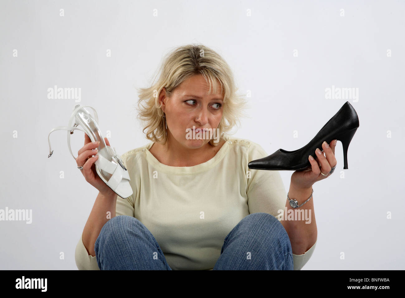 Undecisive woman selecting shoe Stock Photo - Alamy