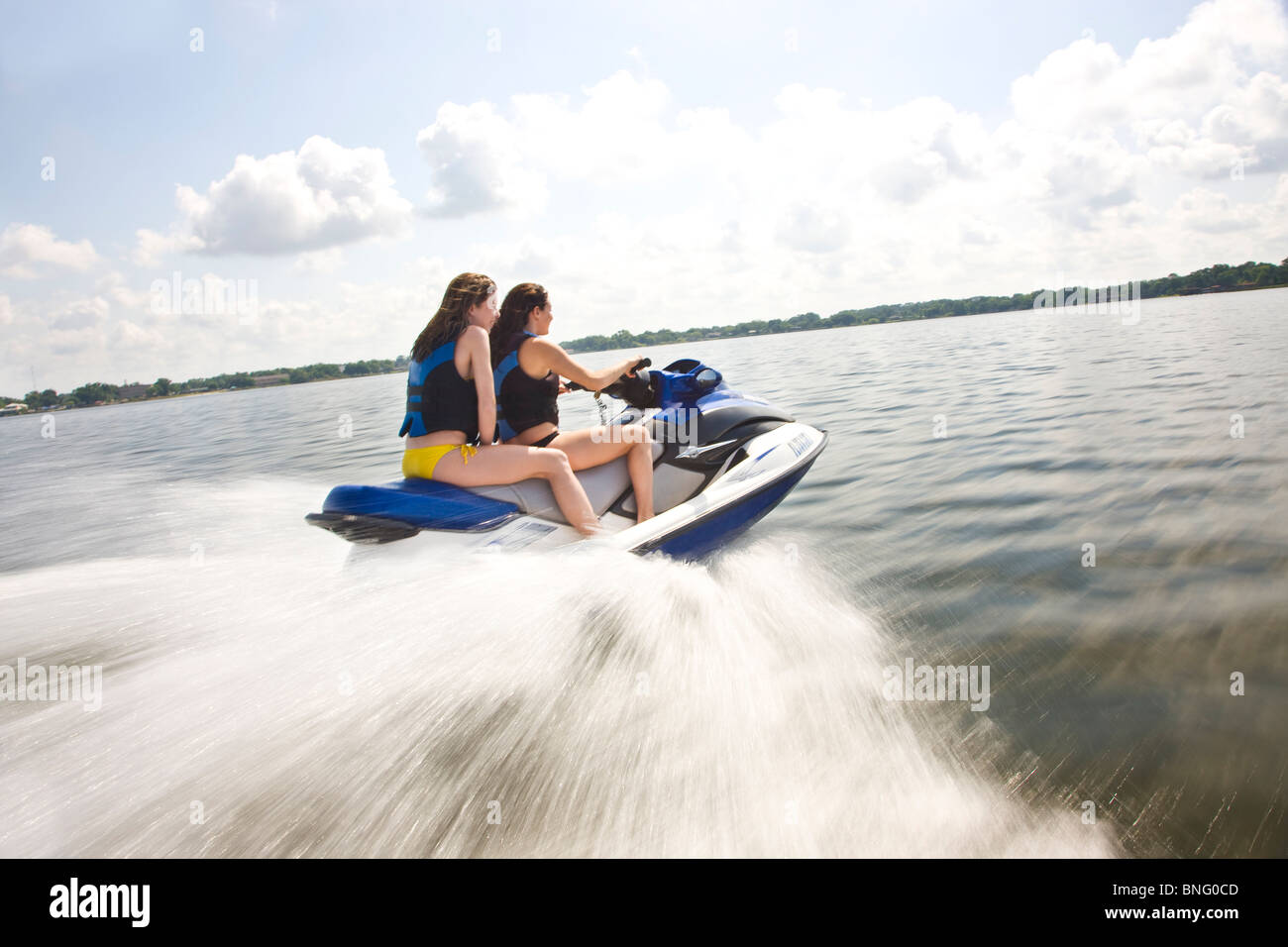 Two young women riding a jet ski Stock Photo - Alamy