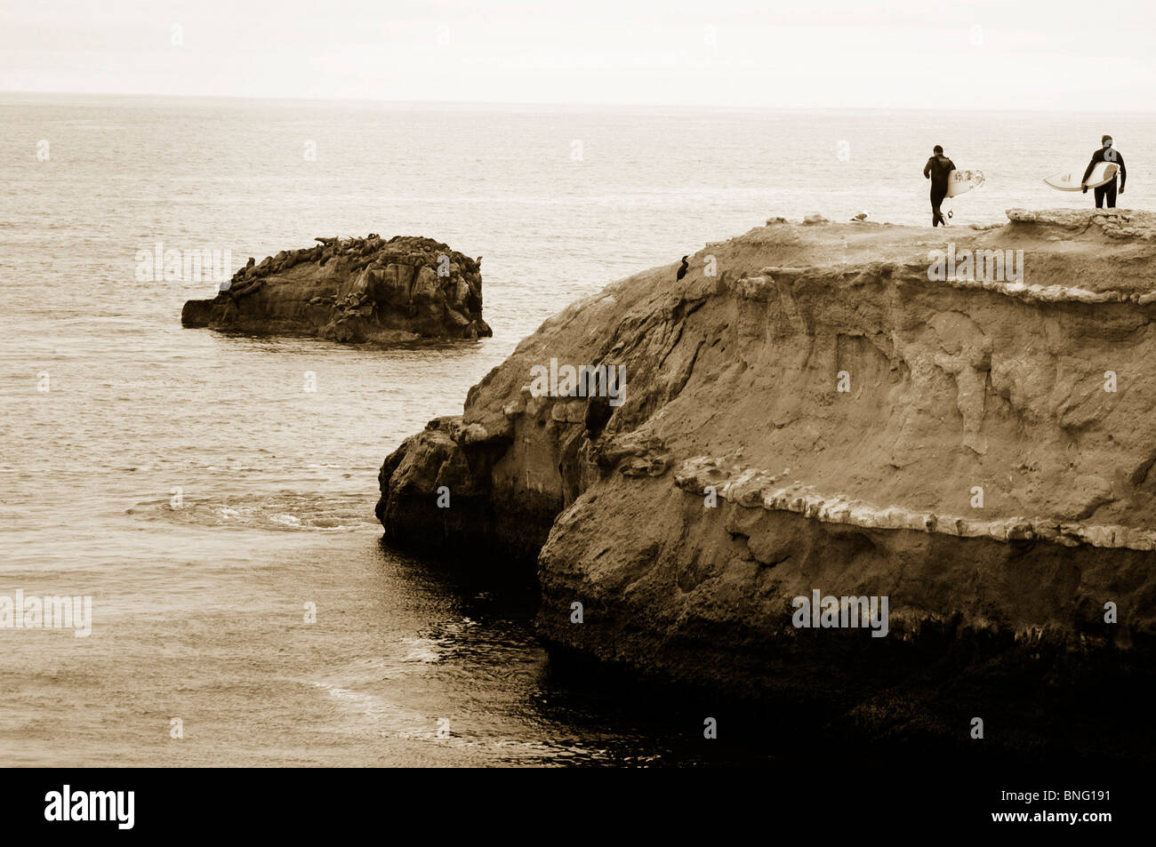 Two surfers carrying surfboards on a cliff, Steamer Lane, Santa Cruz ...