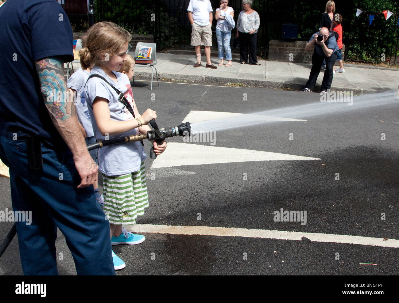 Children try fire brigade hose at London street party Stock Photo - Alamy