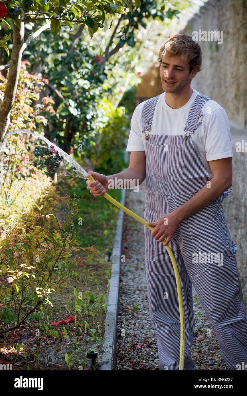 young man watering with hosepipe Stock Photo - Alamy