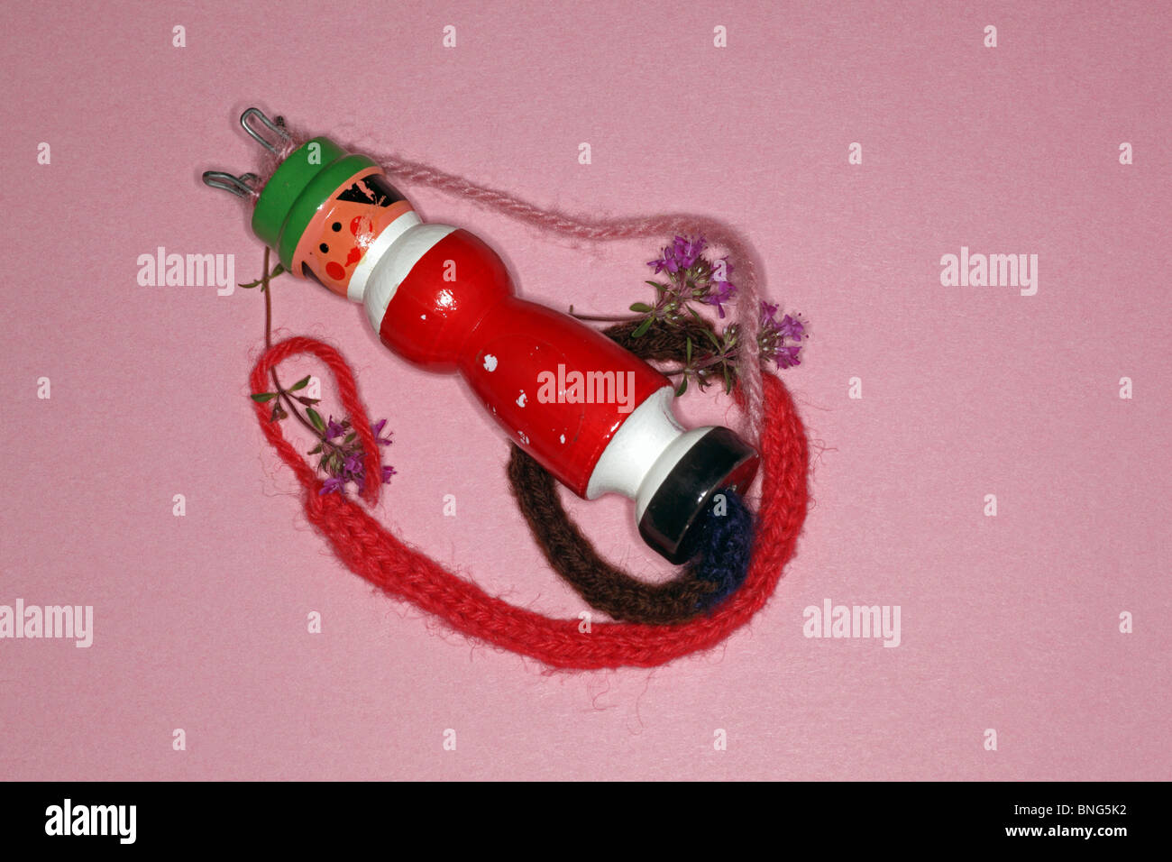 French knitting dolly on pink background with woven woolen string Stock ...