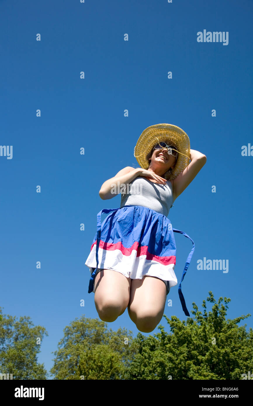 Girl with straw hat and sunglasses jumping Stock Photo - Alamy