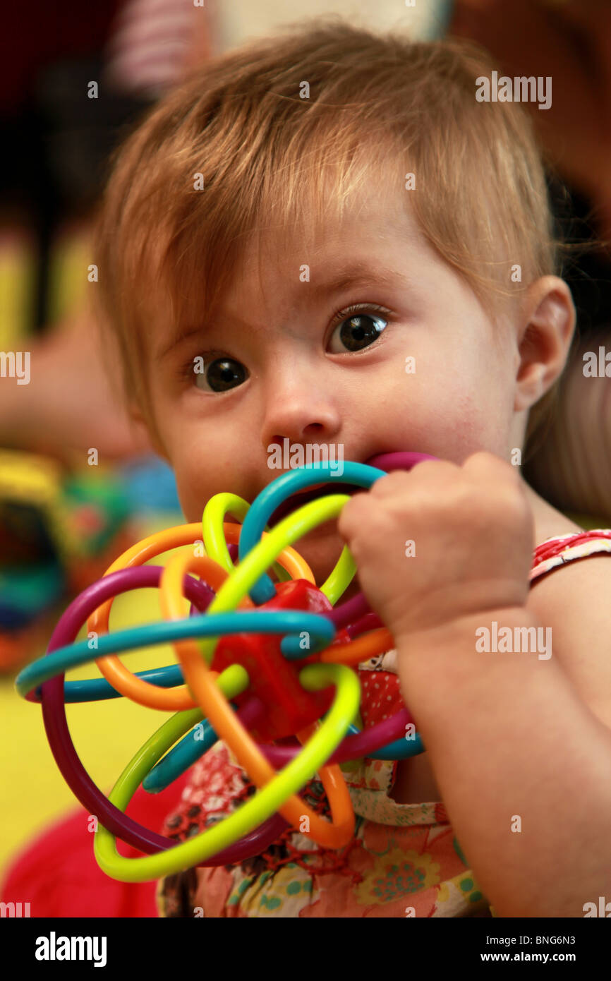 Baby girl biting on a toy Stock Photo - Alamy