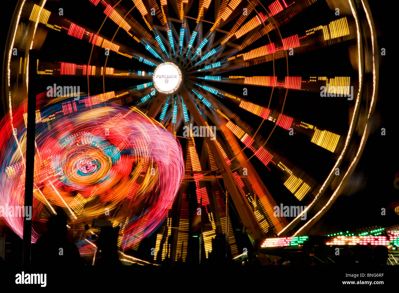 Amusement park rides spin and turn displaying bright colors on a summer ...