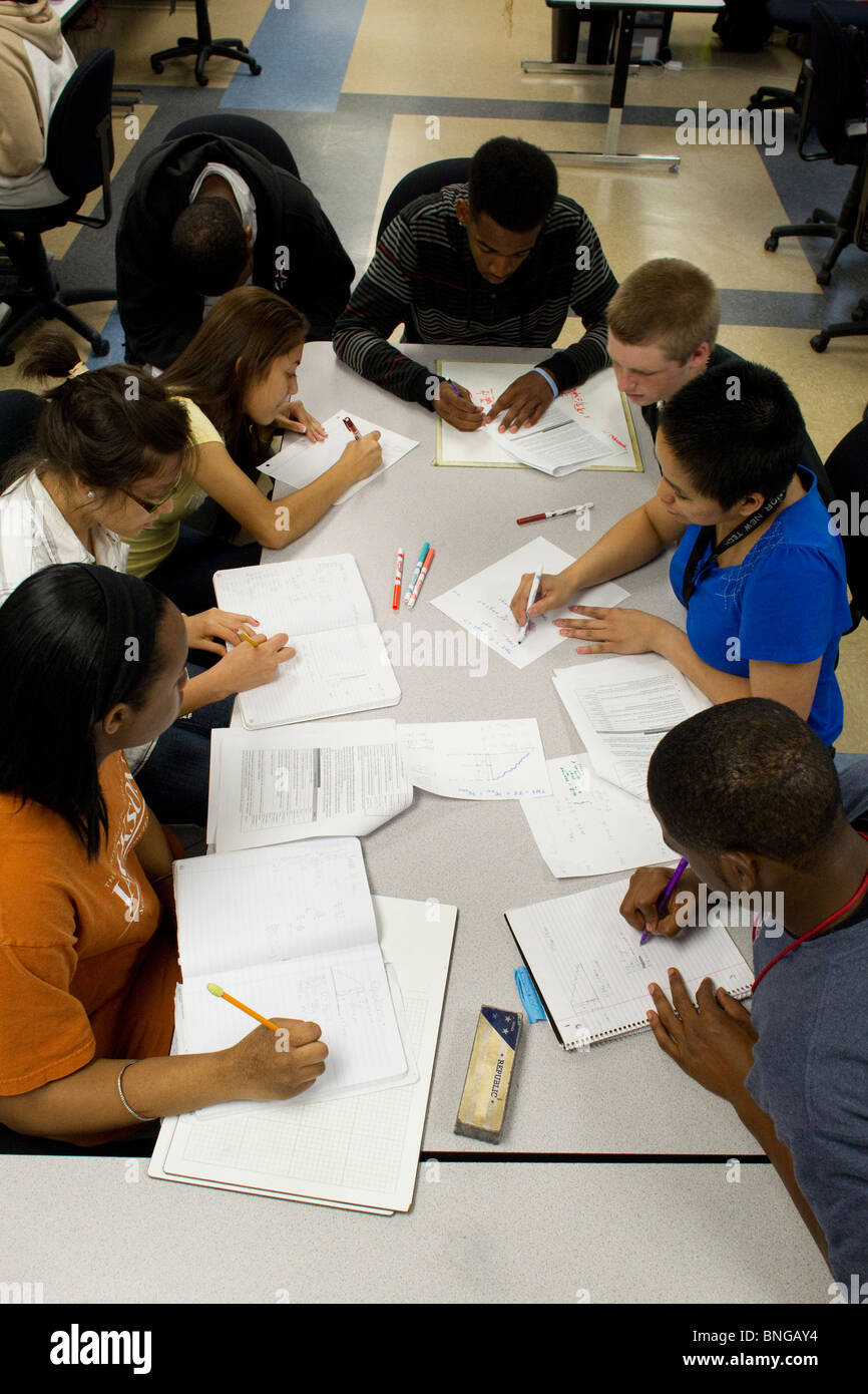 Female physics teacher works with small group of students on problems ...