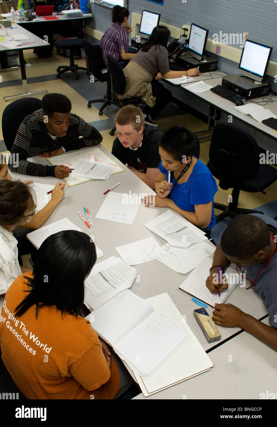 Female physics teacher works with small group of students on problems ...