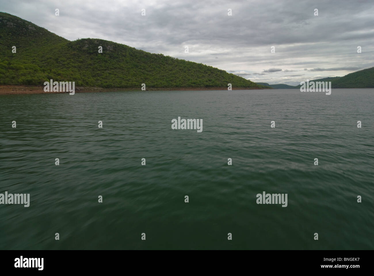 Motion blur of water with tree covered landmass and stormy clouds. Boat ...