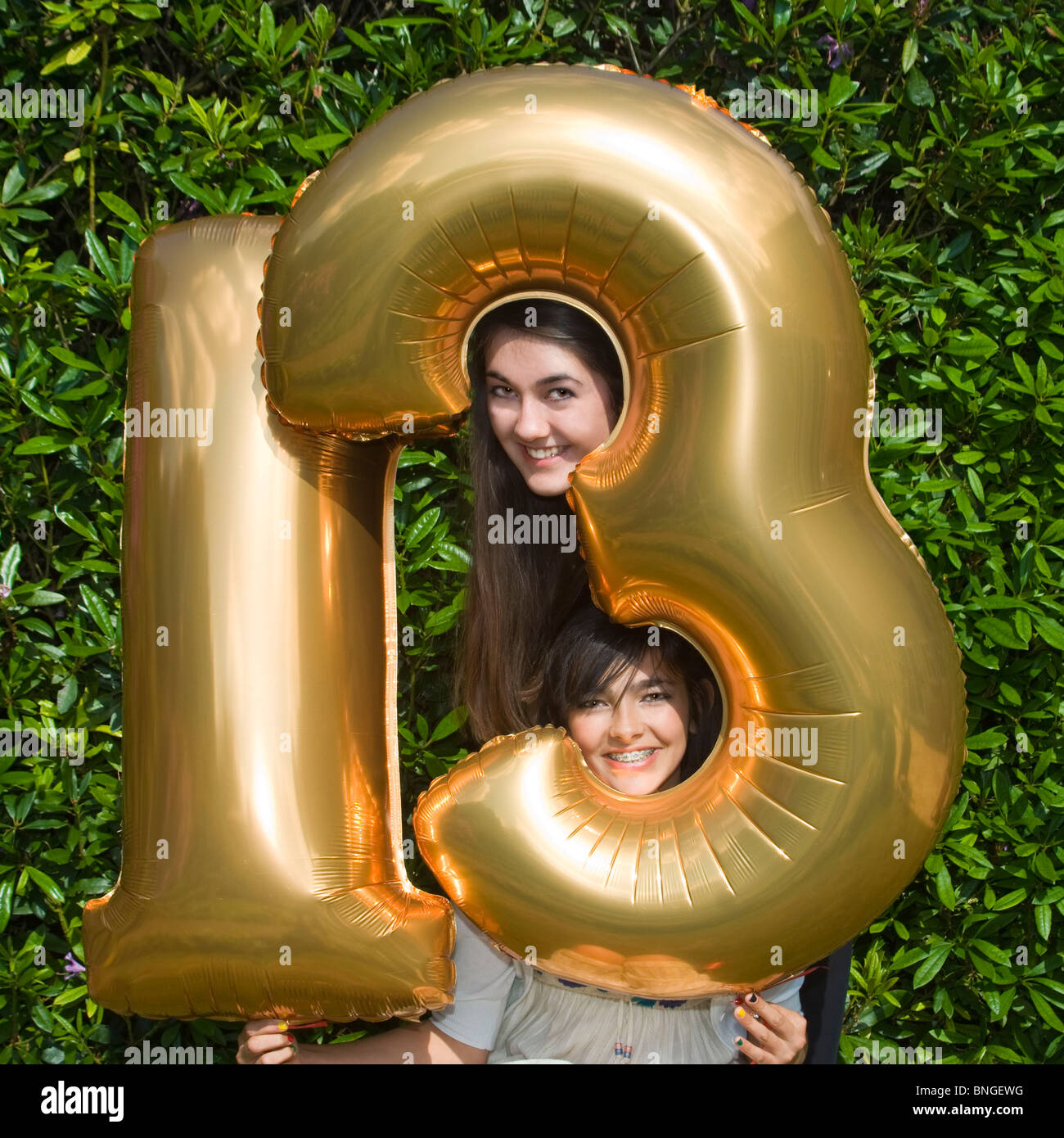 Square portrait of two teenage girls with large gold '13' metallic ...