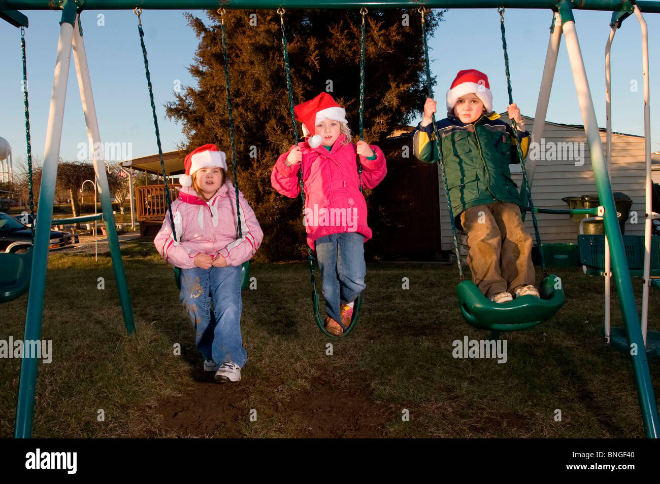 Three girls playing on swings in a park Stock Photo - Alamy