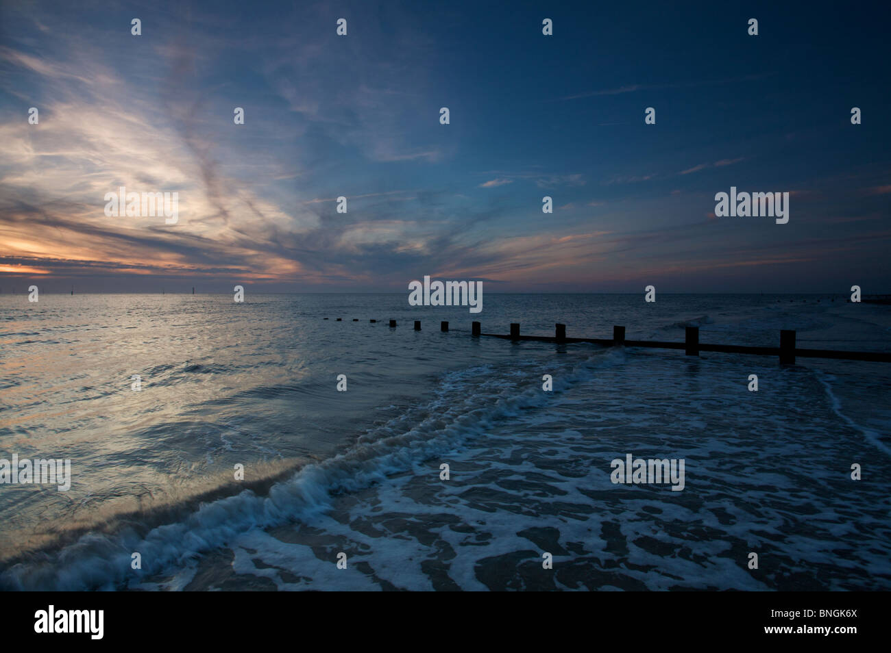 Evening skies at low tide. The wooden groyne (traditional defence ...