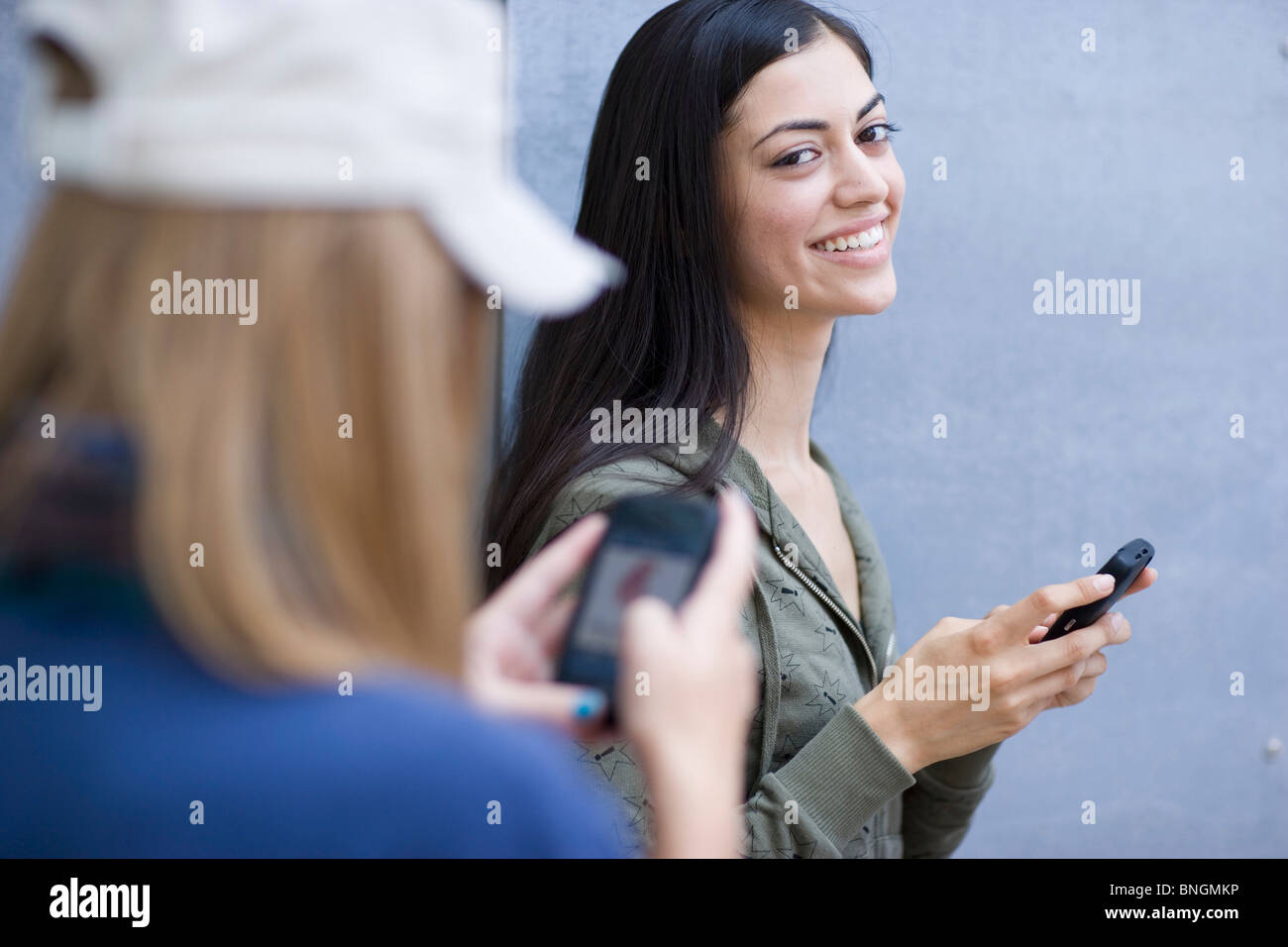 Two female friends text messaging on mobile phones Stock Photo - Alamy