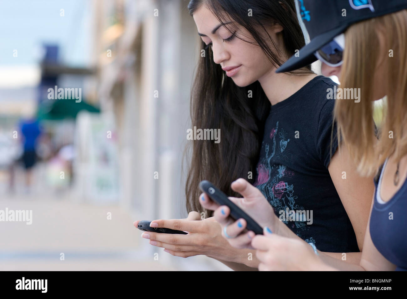 Two female friends text messaging on mobile phones Stock Photo - Alamy