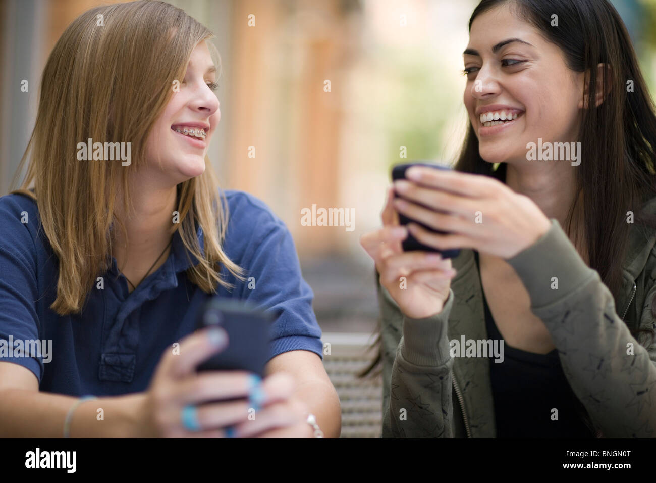Two female friends text messaging on mobile phones Stock Photo - Alamy