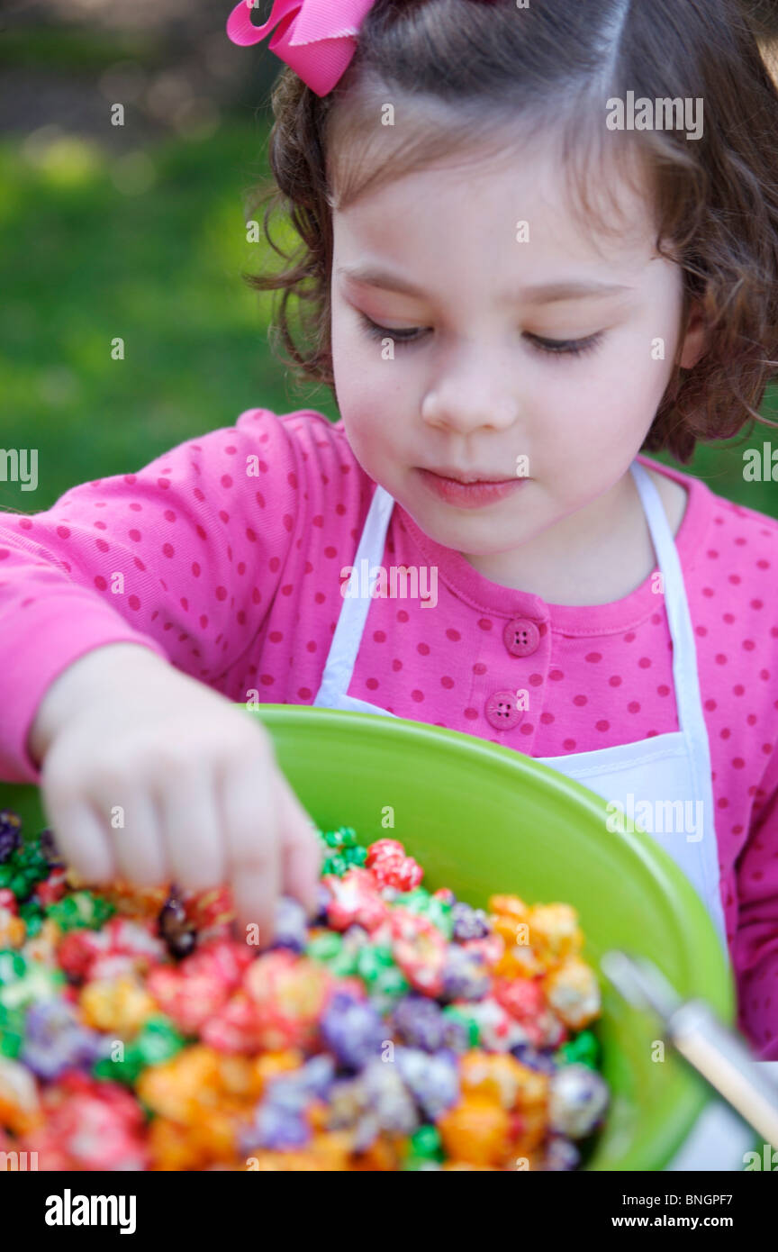 Young girl reaching for colored popcorn Stock Photo - Alamy