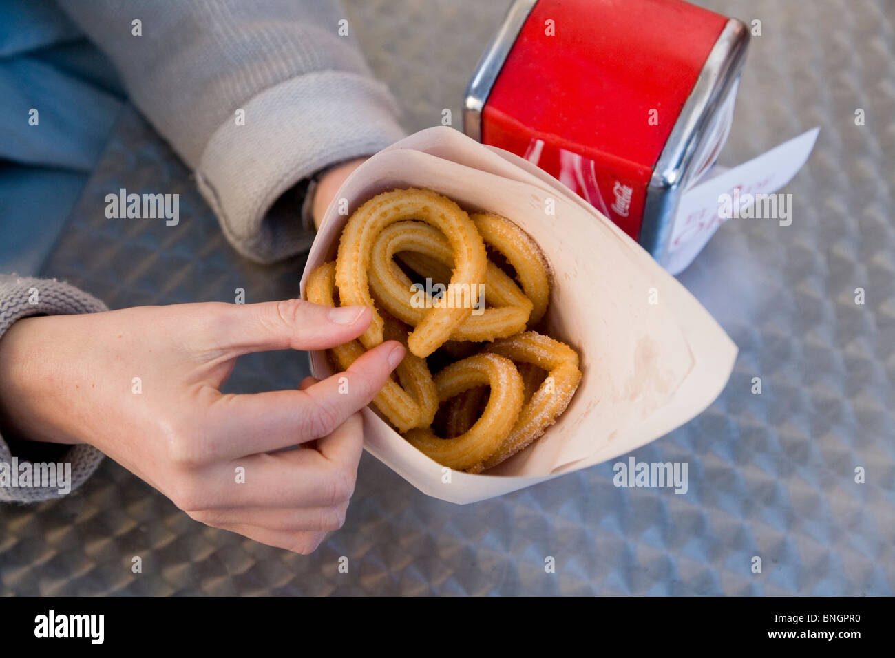Wrapped portion of Churros held in a woman's hand shop at a / bar ...