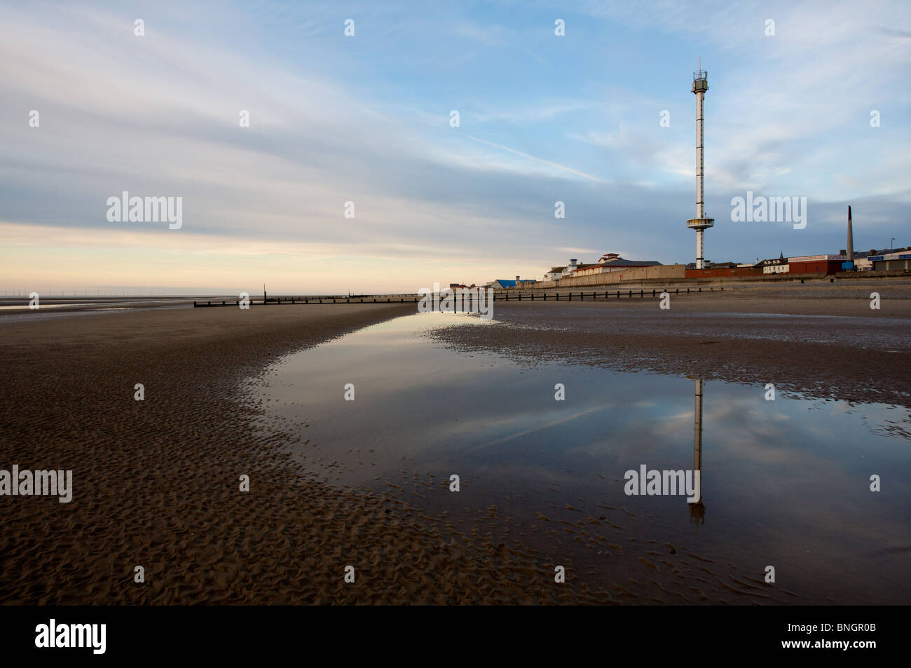 Rhyl sky tower is reflected in standing water on the beach at low tide ...