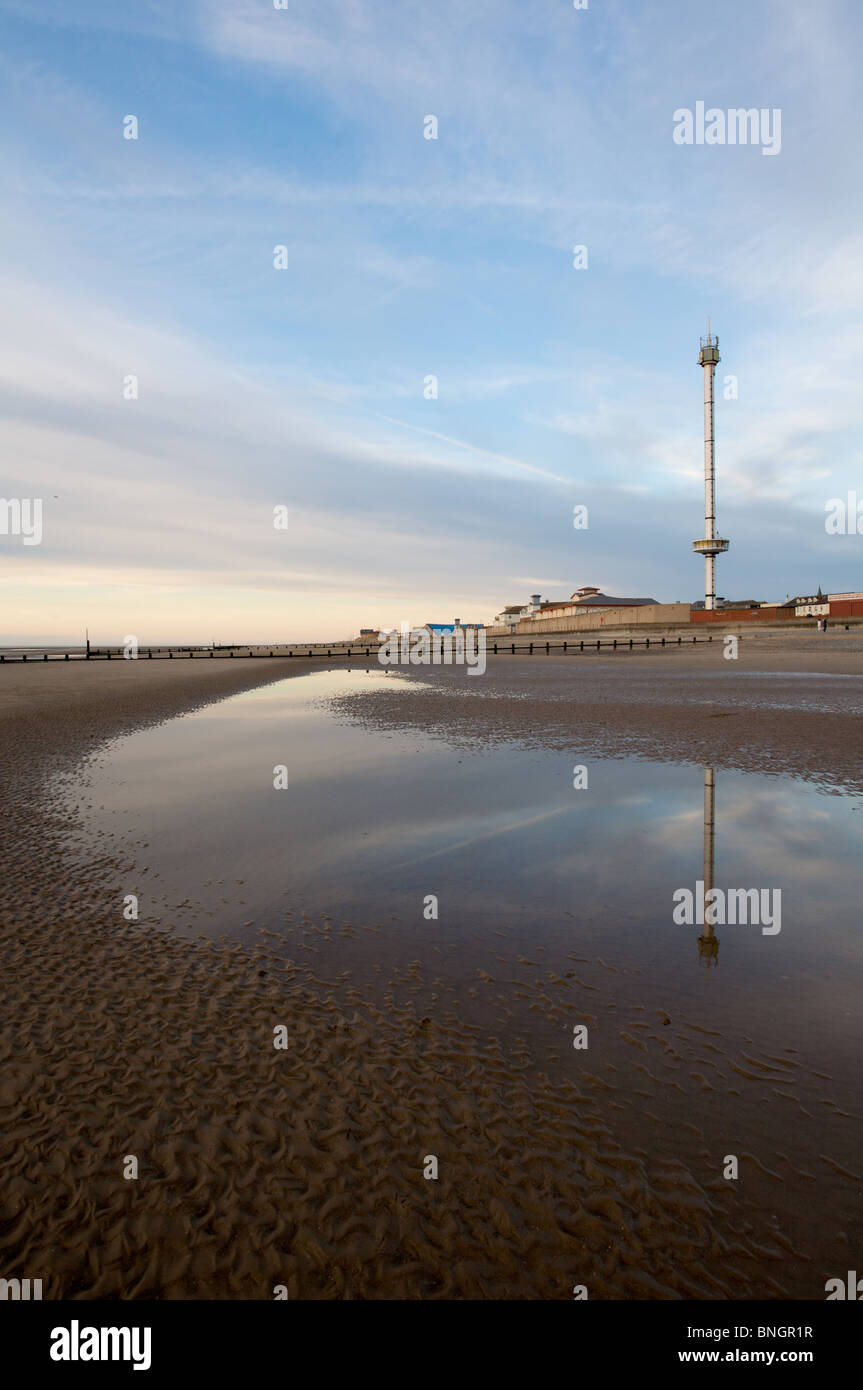 Rhyl sky tower is reflected in standing water on the beach at low tide ...