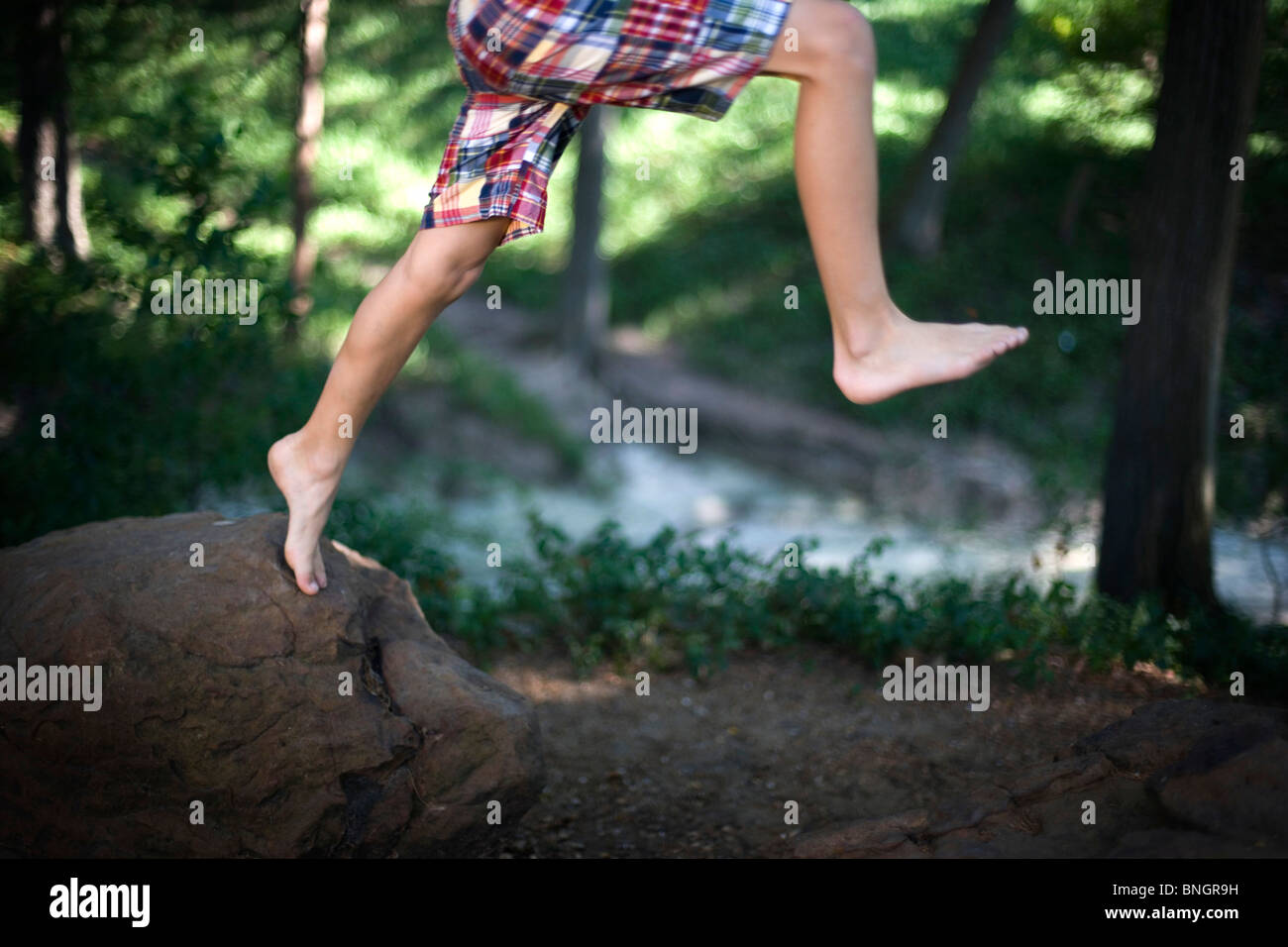 Boy jumping from rock in forest Stock Photo - Alamy