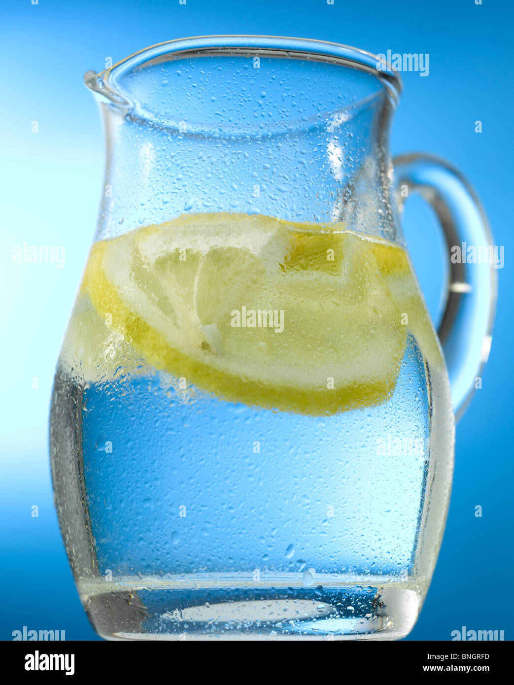 Refreshing lemon water in a jug in front of a blue background Stock ...