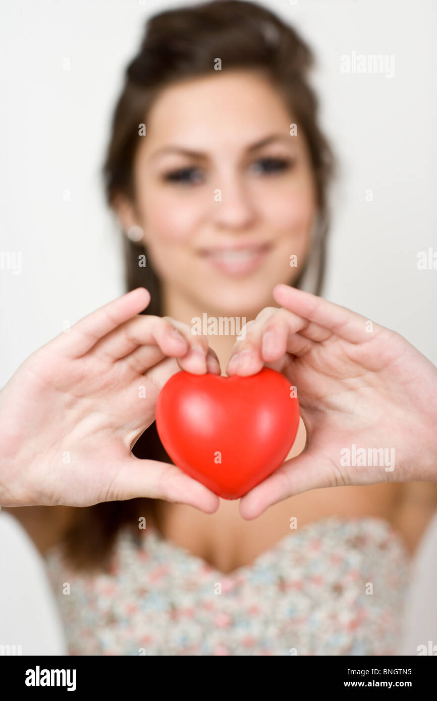 Teenage girl holding a heart shape object Stock Photo - Alamy