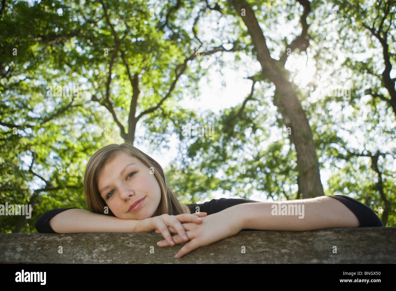 Portrait of a teenage girl leaning on a bench Stock Photo - Alamy