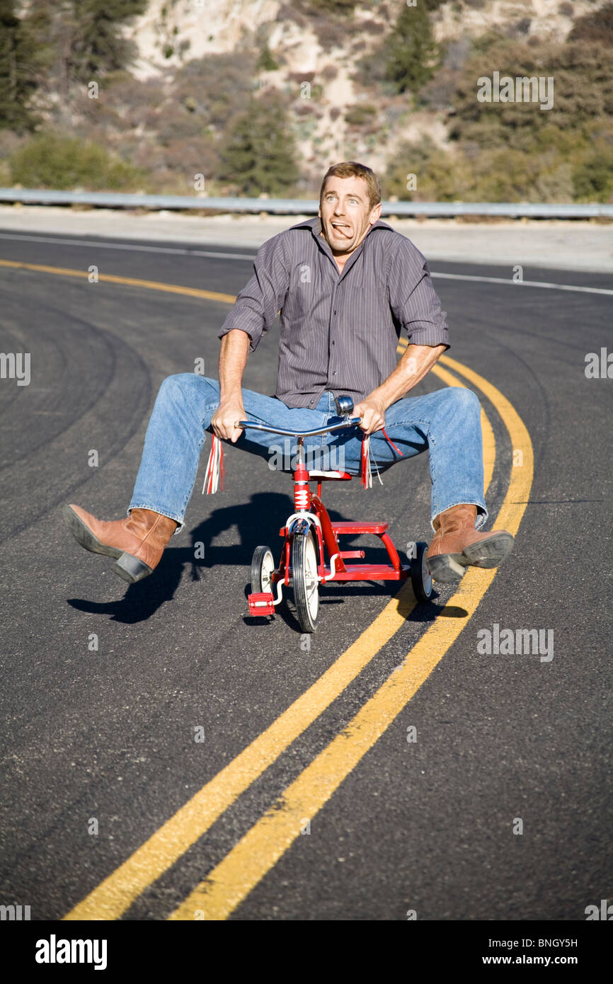 Man acting silly while riding a tricycle Stock Photo - Alamy