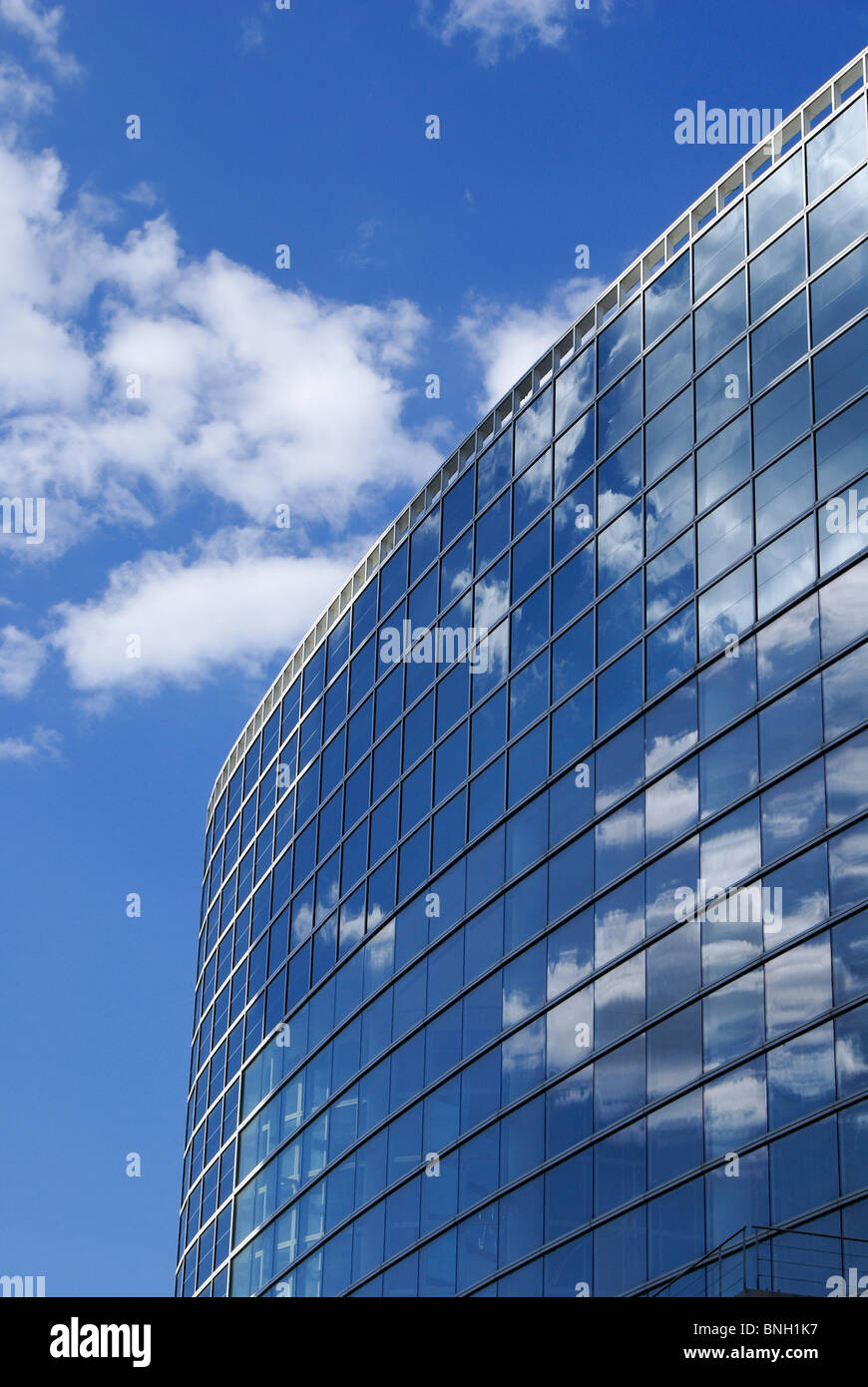 White clouds and a blue sky reflecting in the mirrored windows of a ...