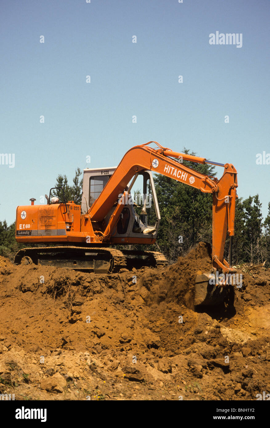 Orange backhoe digging dirt Stock Photo - Alamy