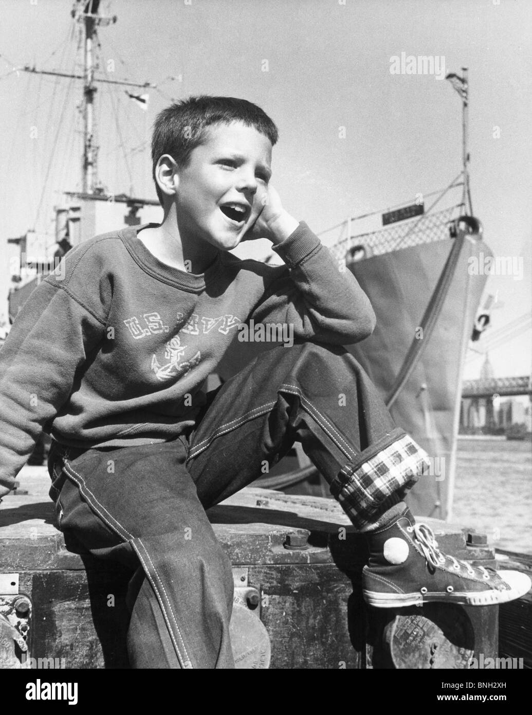 Boy sitting at a harbor Stock Photo - Alamy