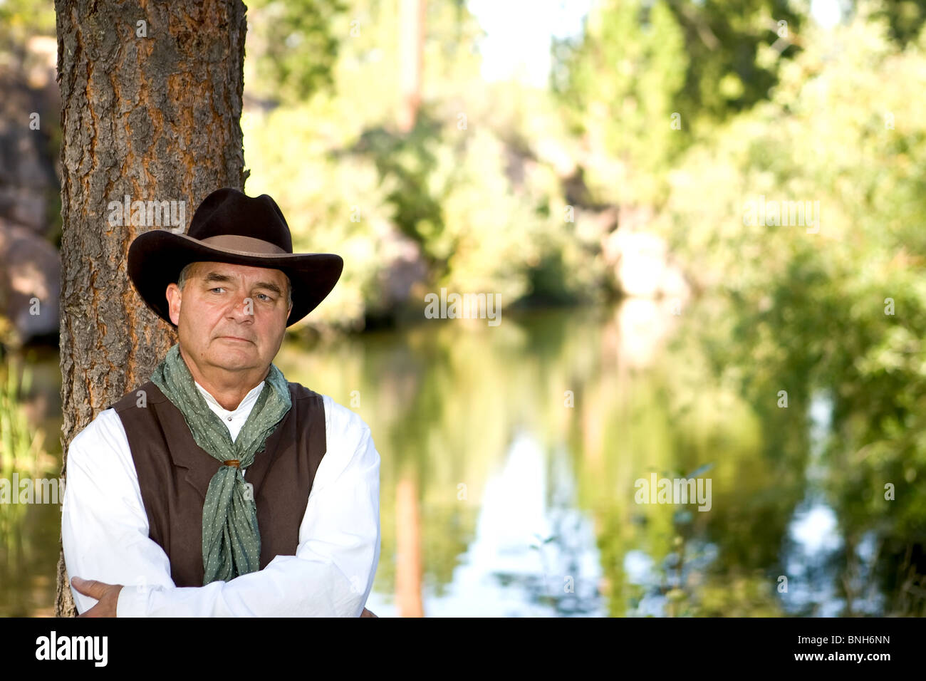 Handsome older cowboy, leaning against a tree Stock Photo - Alamy