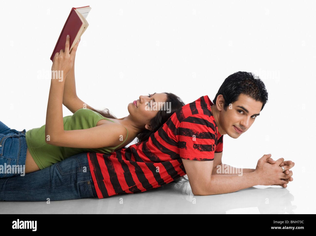 Woman lying on a man's back and reading a book Stock Photo - Alamy