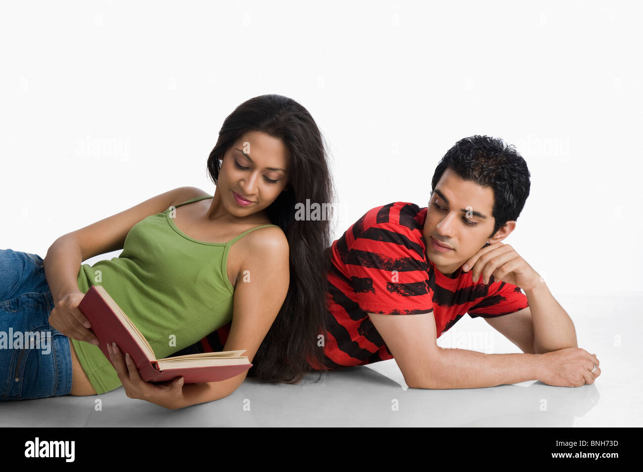 Woman leaning on a man's back and reading a book Stock Photo - Alamy
