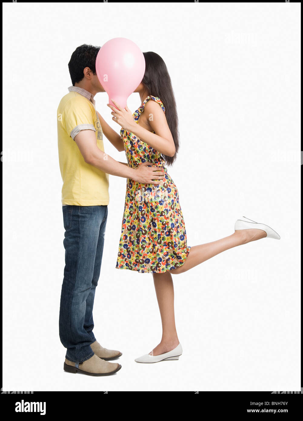 Couple kissing behind a balloon Stock Photo - Alamy