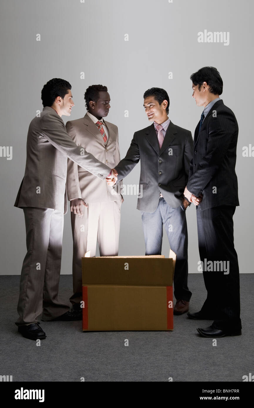 Two businessmen shaking hands over an illuminated cardboard box with ...