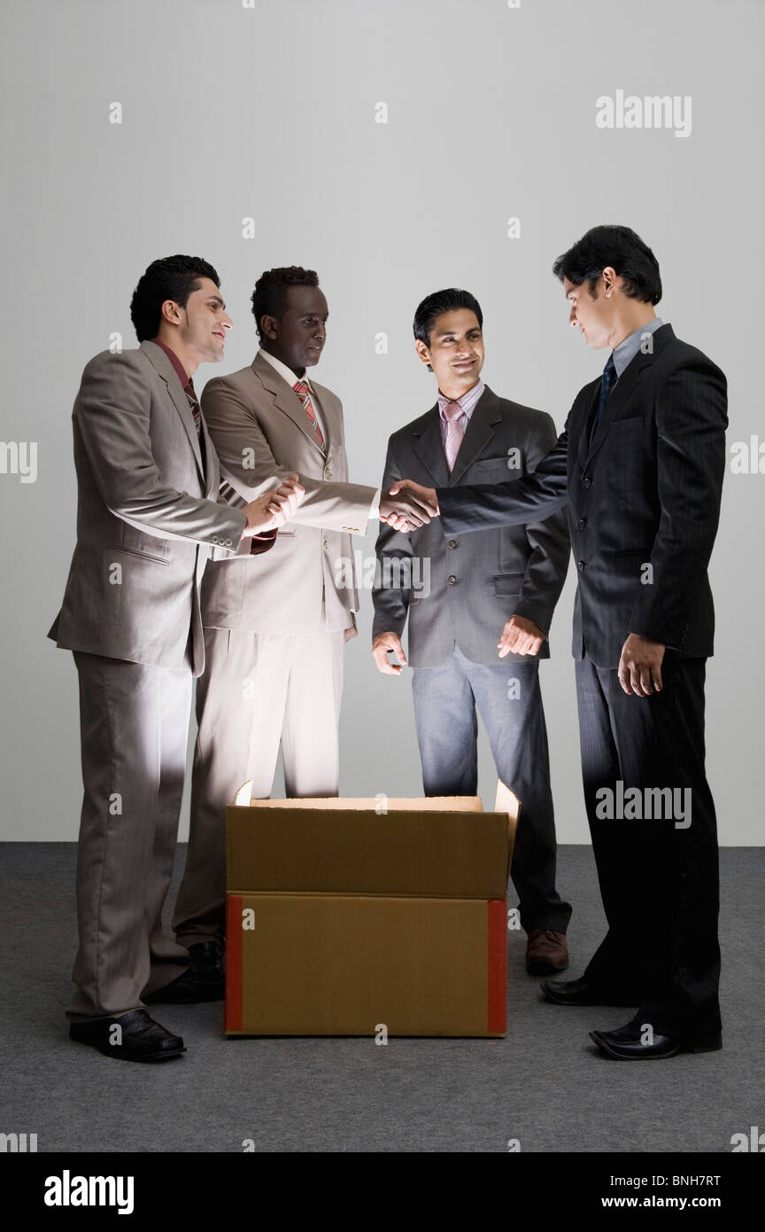 Two businessmen shaking hands over an illuminated cardboard box with ...