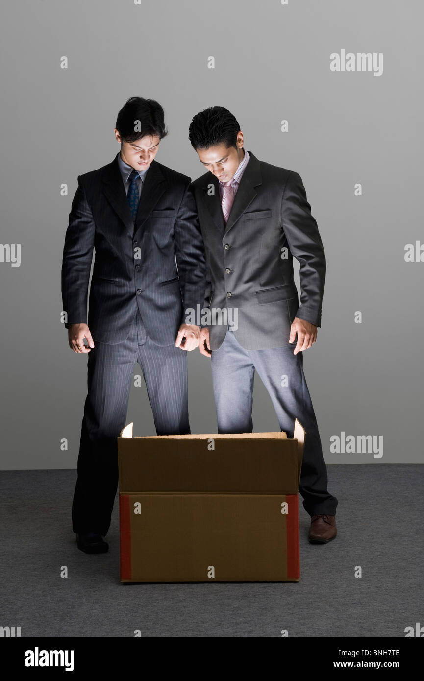Two businessmen looking into an illuminated cardboard box Stock Photo ...