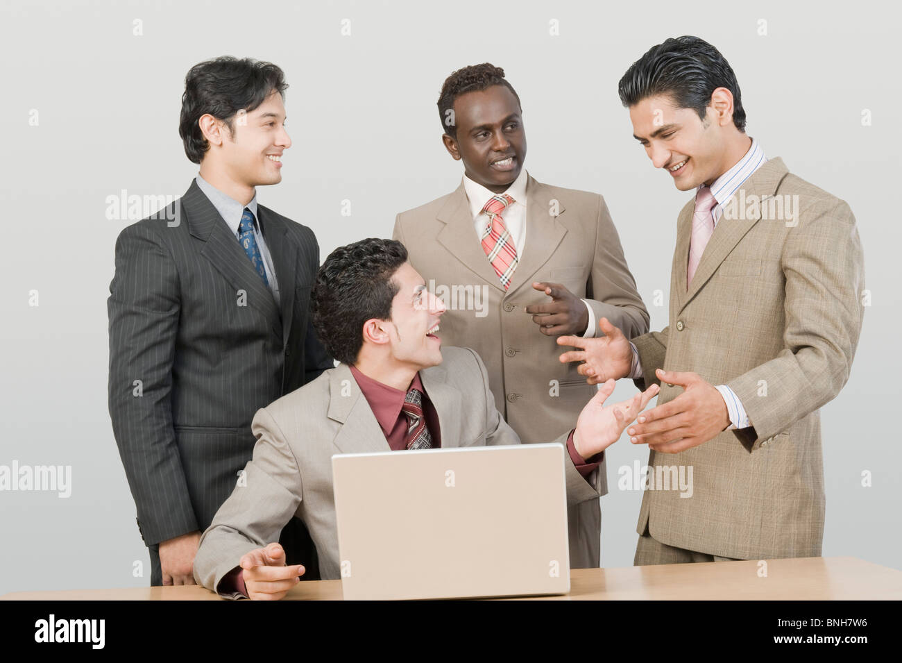 Four businessmen talking in front of a laptop Stock Photo - Alamy Four businessmen talking in front of a laptop Stock Photo - Alamy