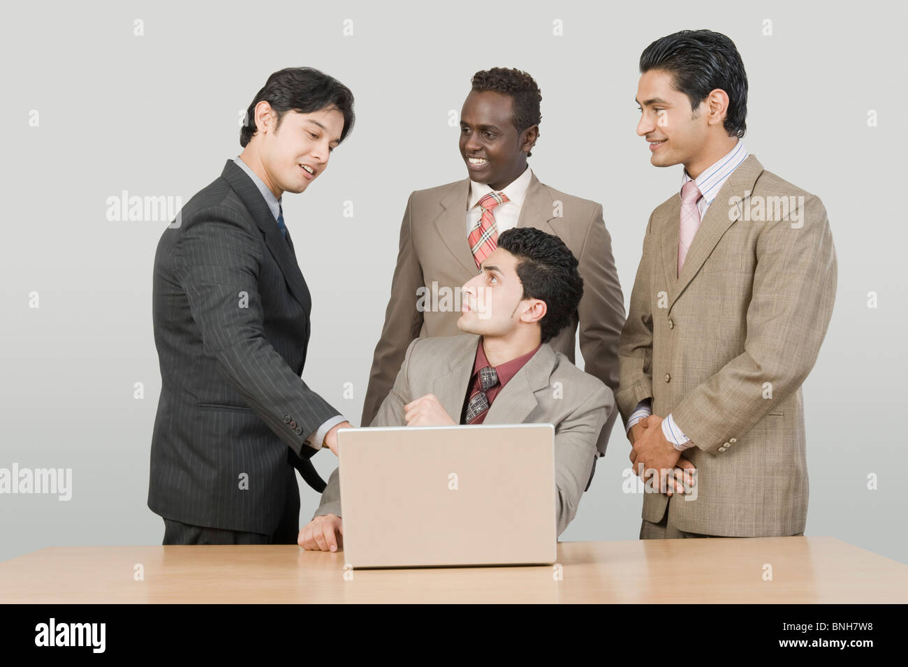 Four businessmen talking in front of a laptop Stock Photo - Alamy