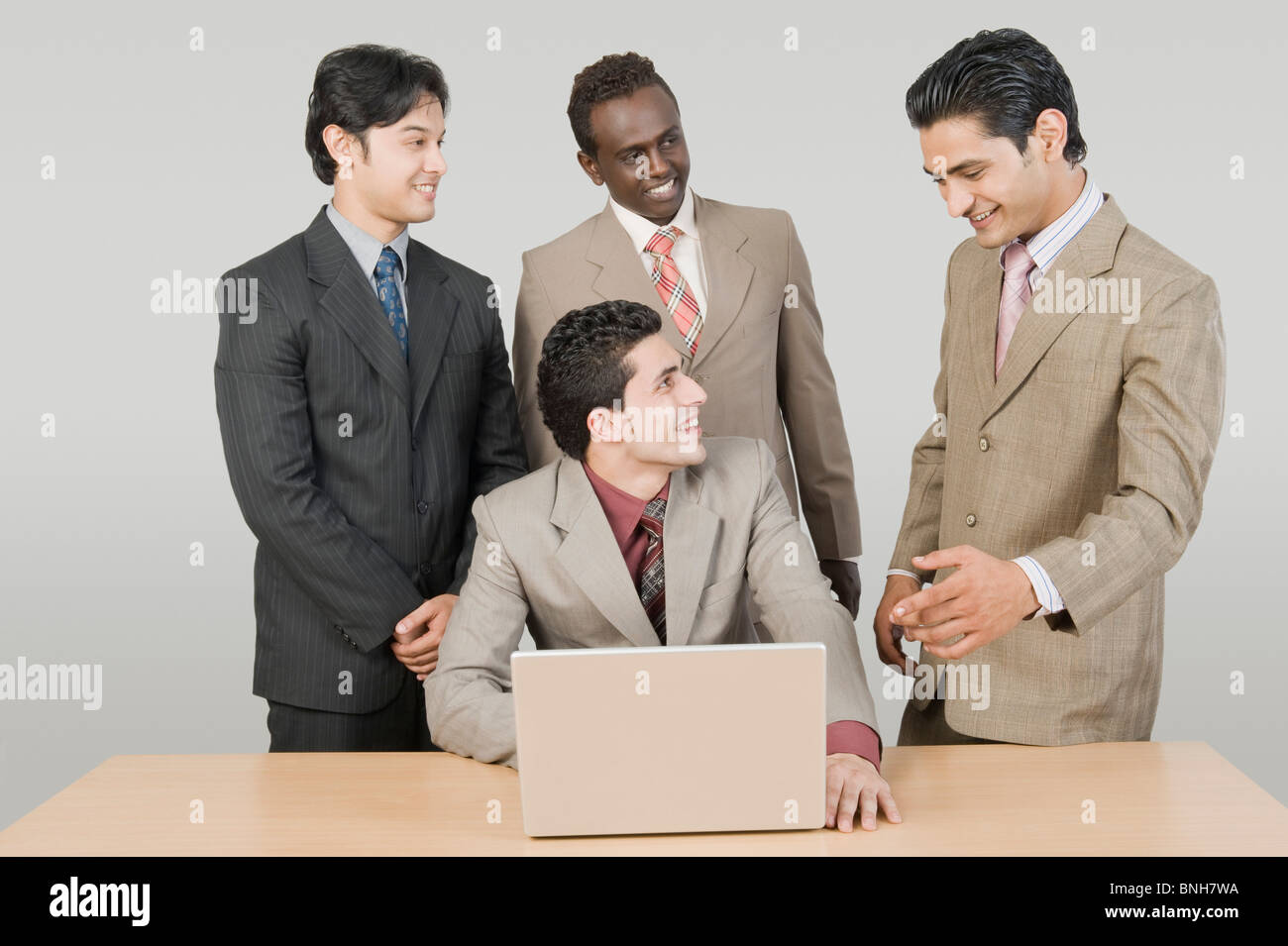 Four businessmen talking in front of a laptop Stock Photo - Alamy