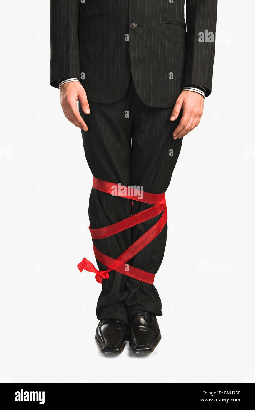Businessman's legs tied up with a ribbon Stock Photo - Alamy