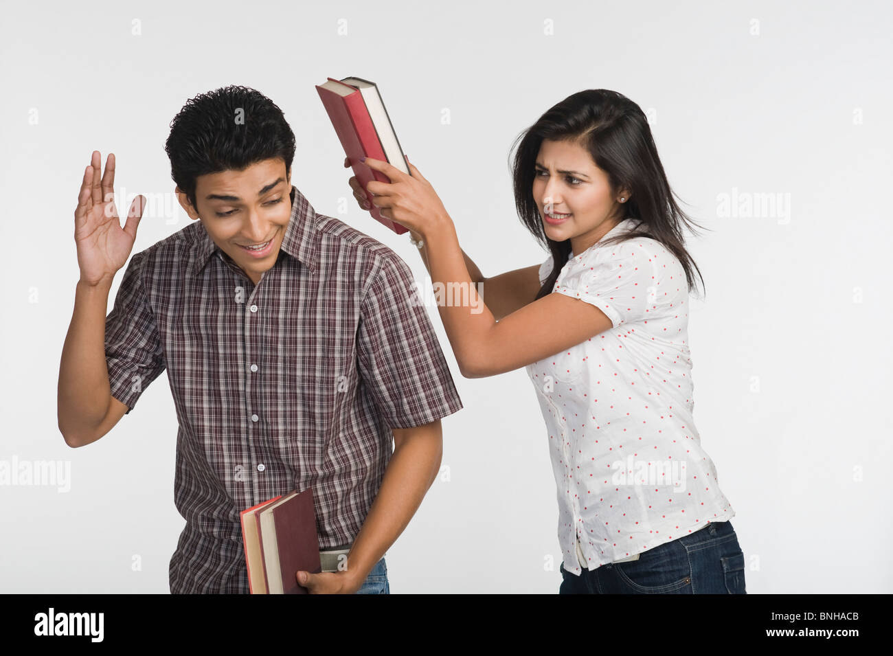 Woman beating her friend with a book Stock Photo - Alamy