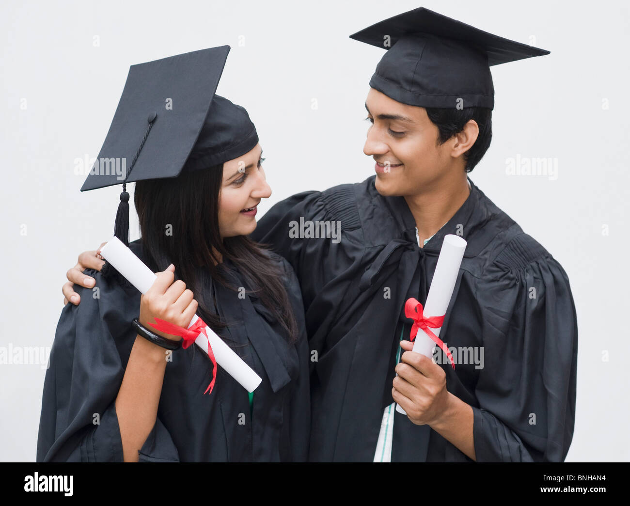 Couple in graduation gown holding diplomas and smiling Stock Photo - Alamy