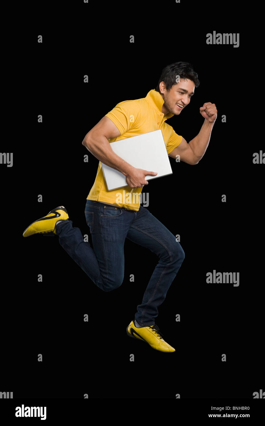 Man carrying a laptop and smiling Stock Photo - Alamy