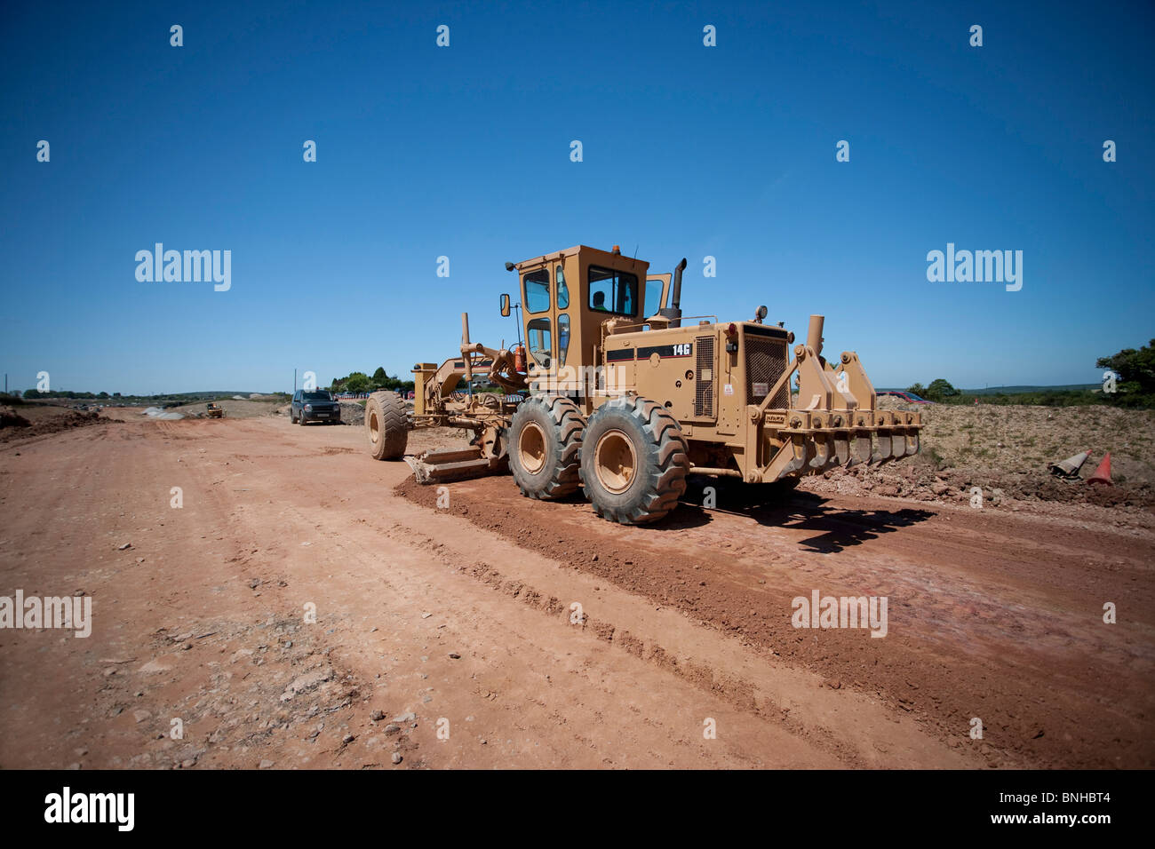 Heavy earth grader on road construction site Stock Photo - Alamy