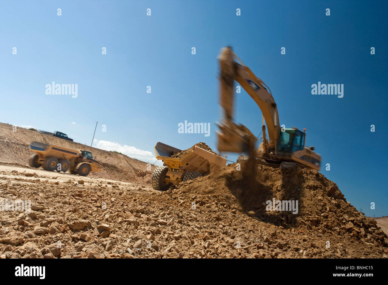 Articulated earth mover and excavator on road construction site Stock ...