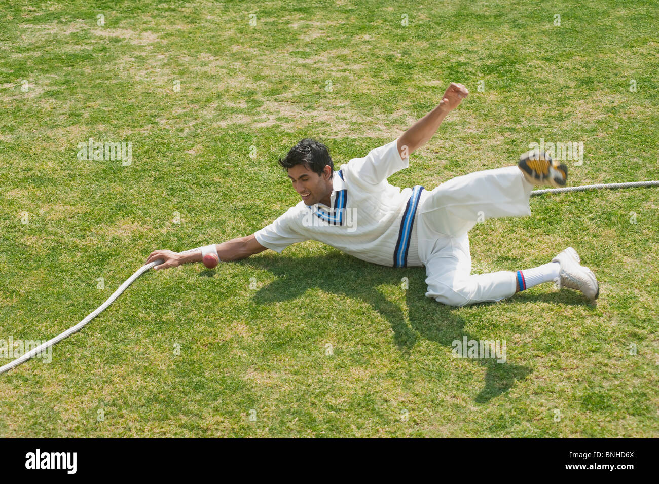 Cricket fielder diving to stop a ball near boundary line Stock Photo ...