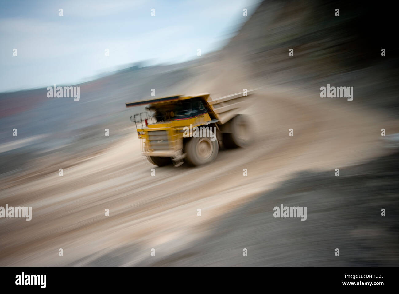 Large earth mover haul dump truck in quarry heading down dirt road with ...