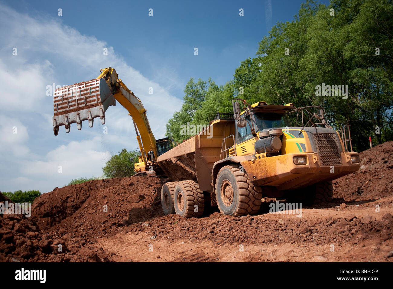 Excavator and articulated earth mover haul dump truck in quarry or mine ...