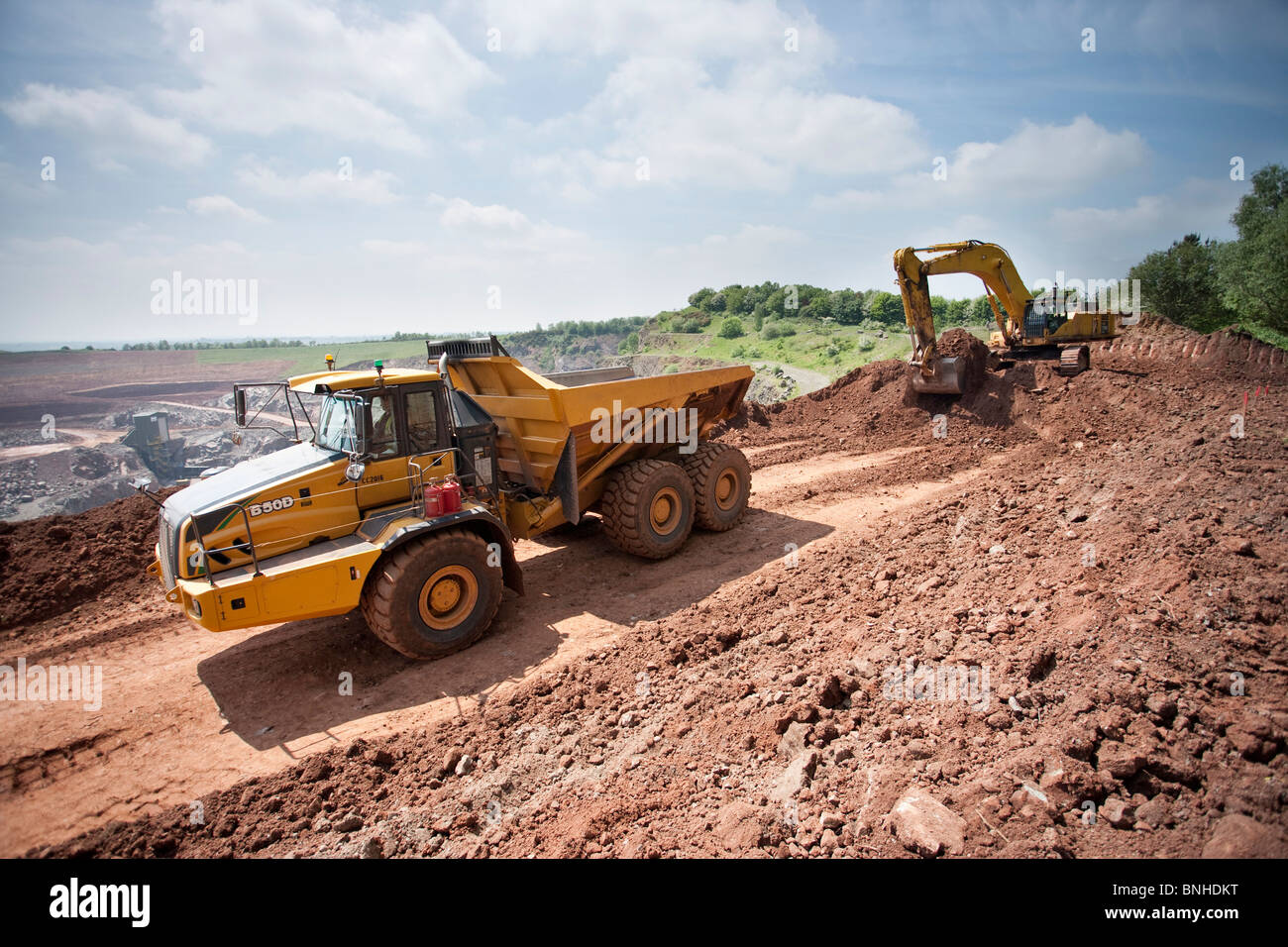 Articulated earth moving truck and excavator near mine or quarry Stock ...